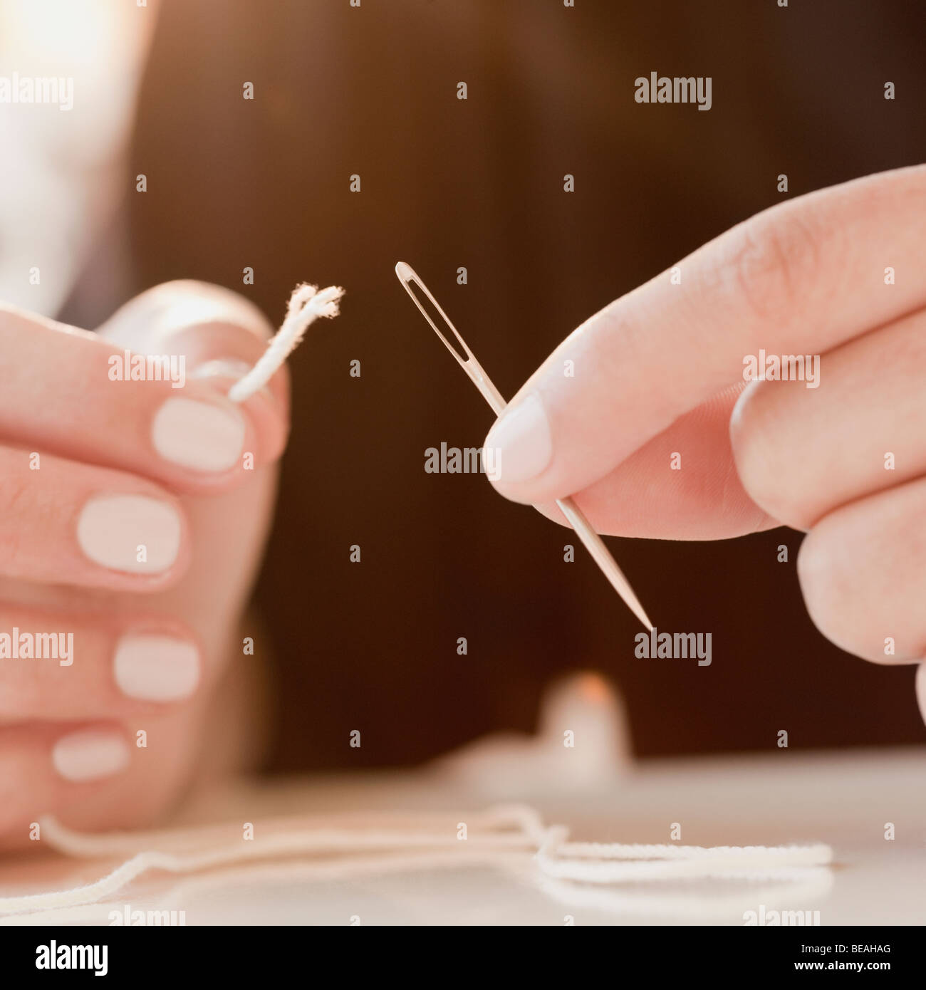 Woman stringing frayed thread through needle Stock Photo - Alamy