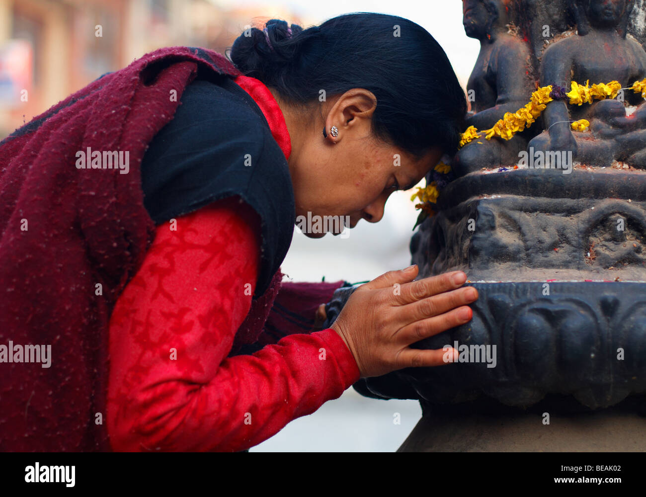 Buddhist woman praying at a Buddhist Statue at Boudhanath Stupa Stock ...