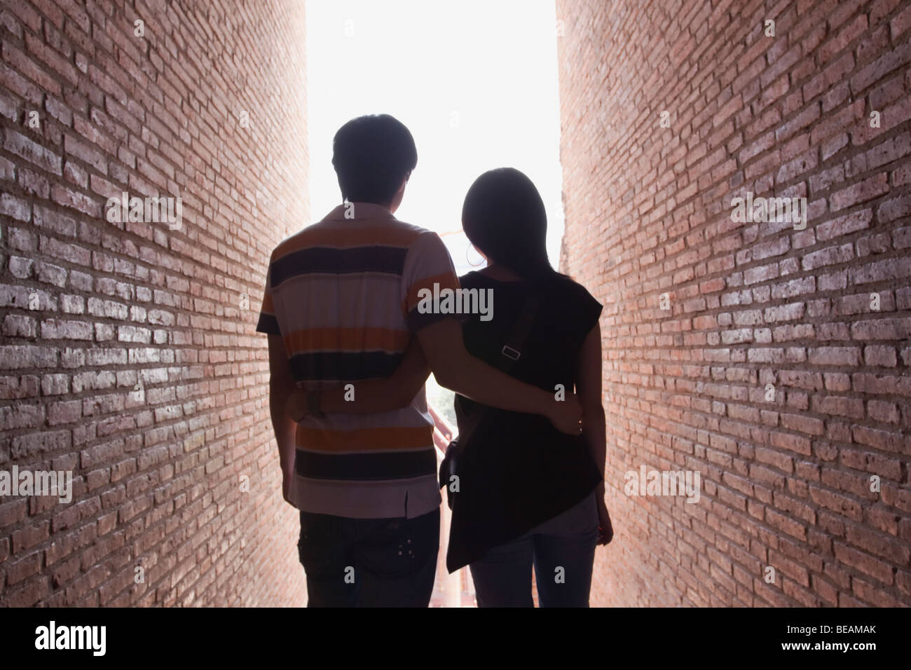 Asian couple walking between brick walls Stock Photo - Alamy