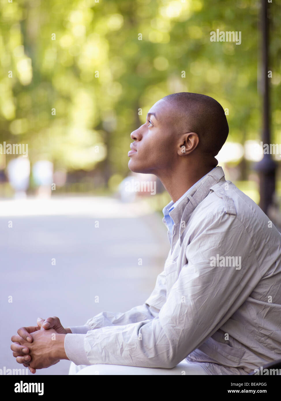 African man looking up with hands clasped Stock Photo - Alamy