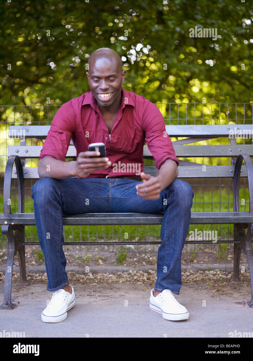 Smiling African man looking down at cell phone Stock Photo - Alamy