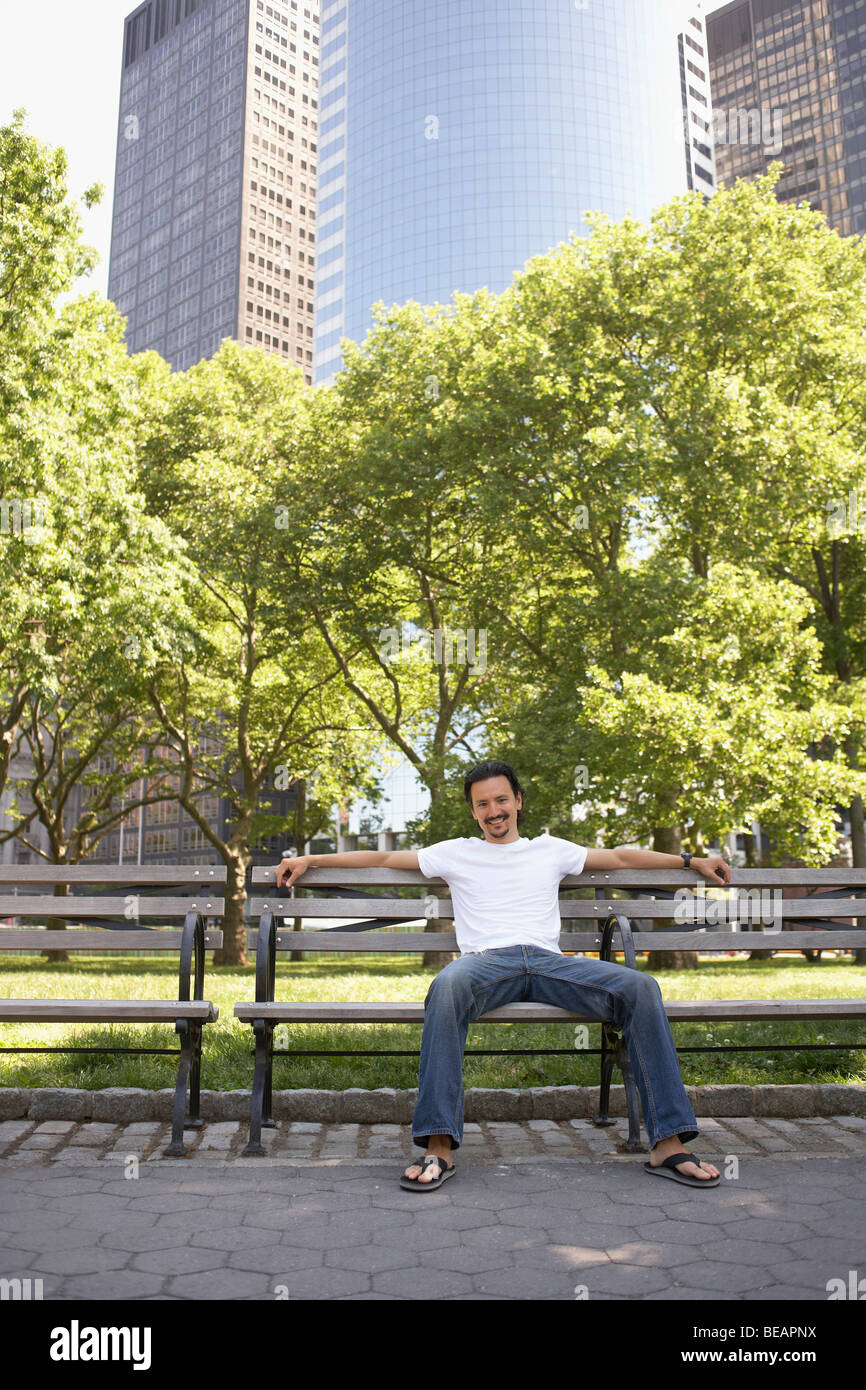 Mixed race man smiling on park bench Stock Photo - Alamy