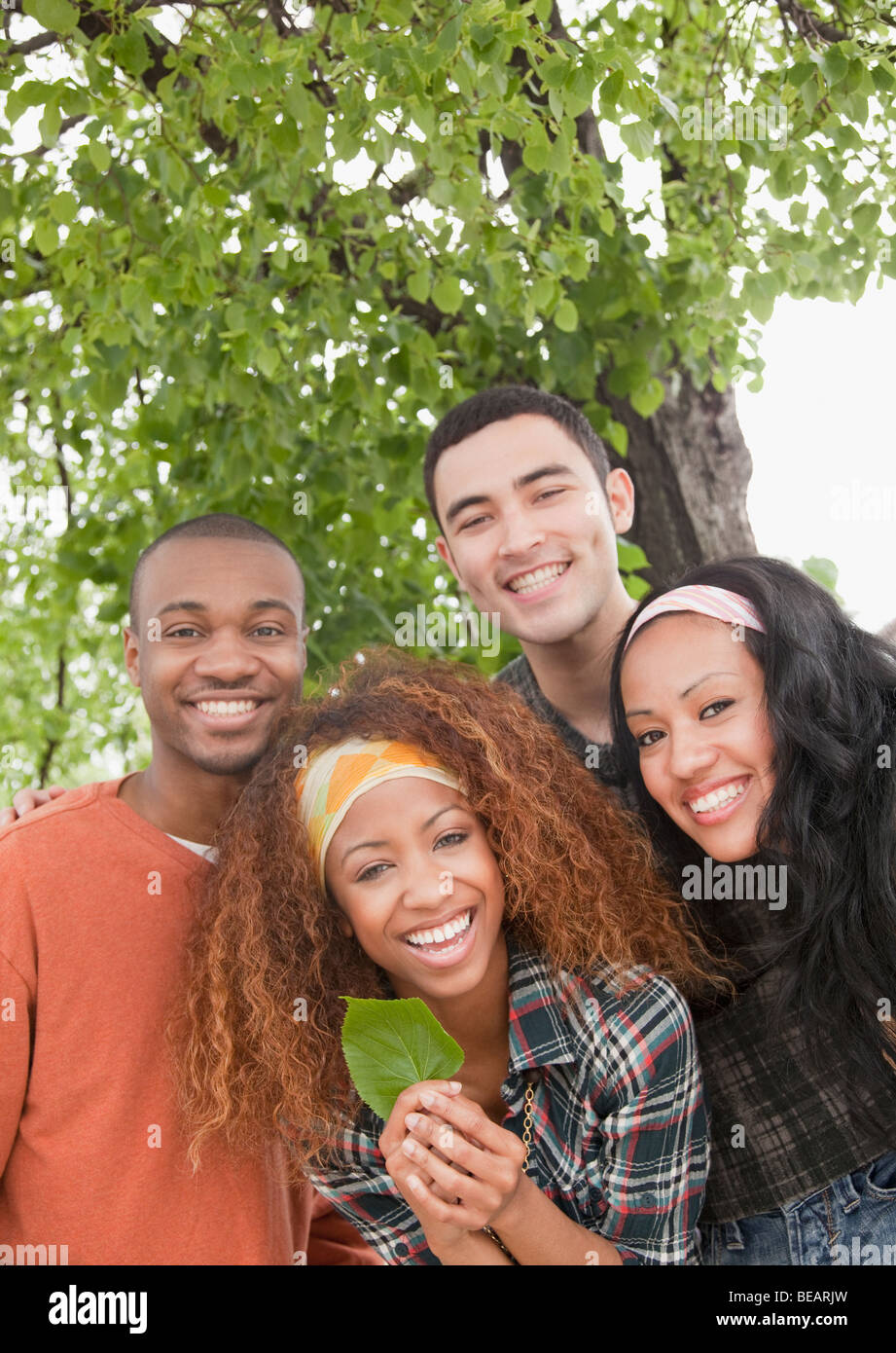 Friends holding leaf under tree Stock Photo - Alamy