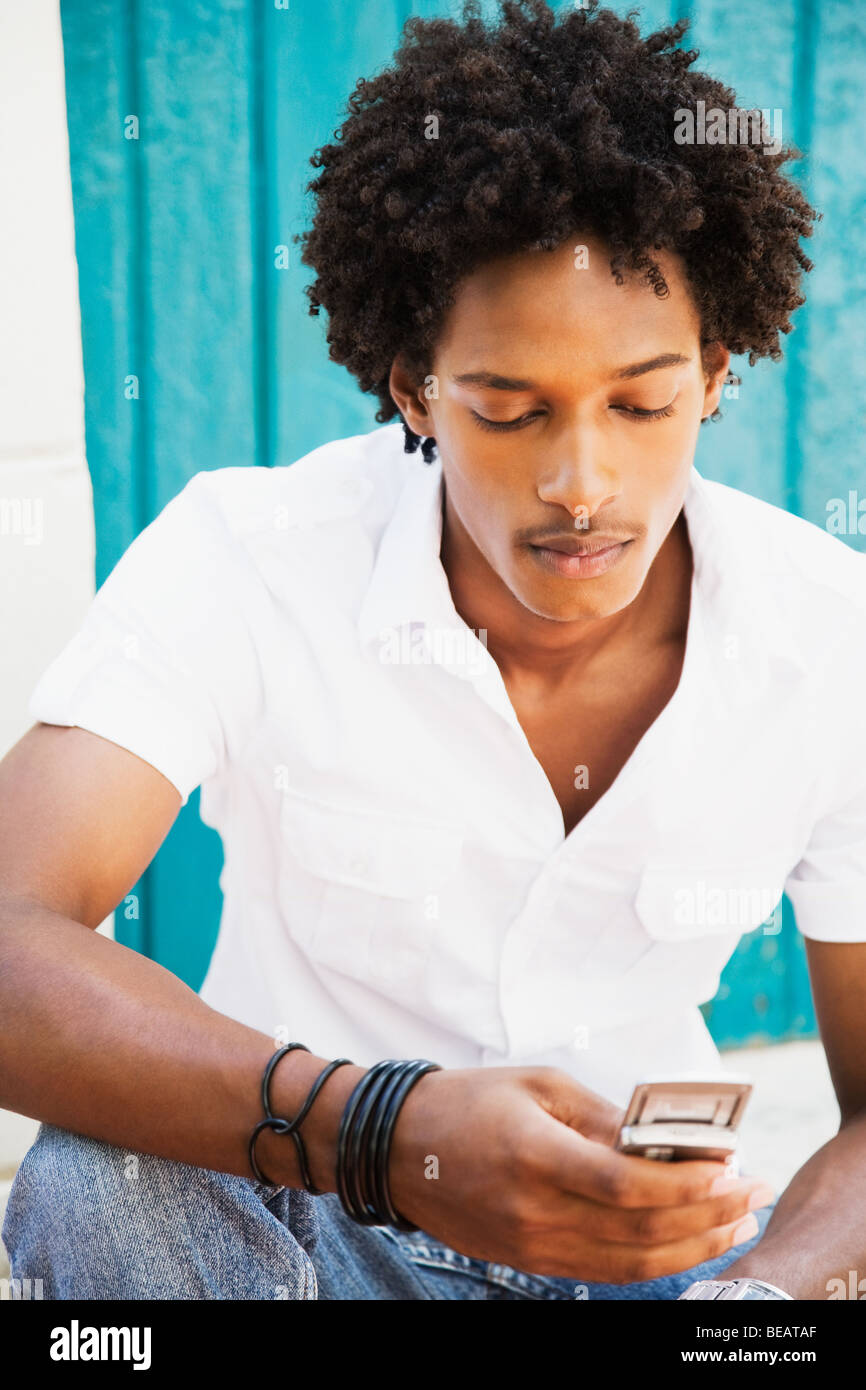 African man looking down at cell phone Stock Photo - Alamy