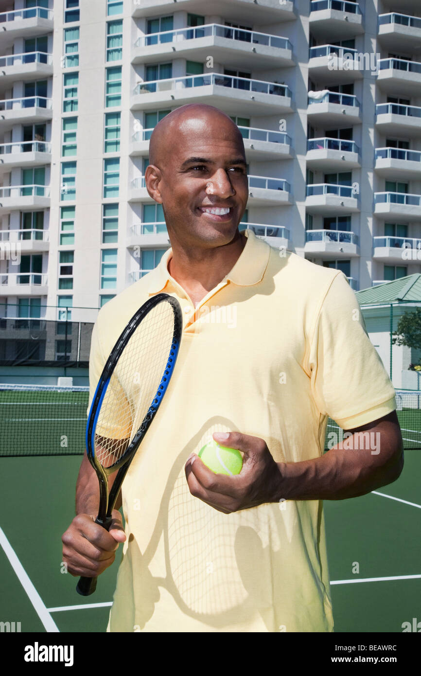African man holding tennis ball and racket Stock Photo - Alamy