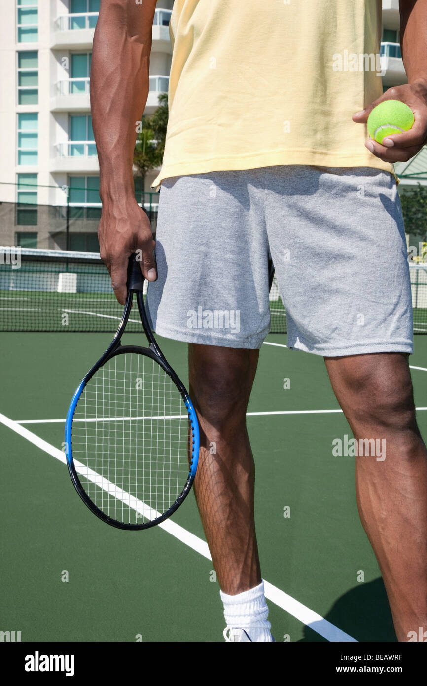 African man holding tennis ball and racket Stock Photo - Alamy