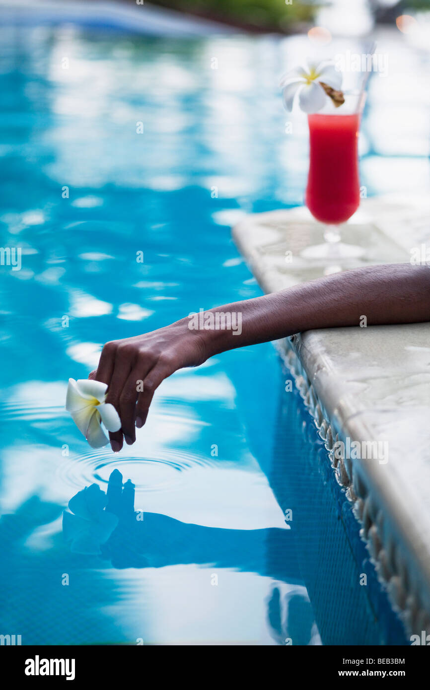 Woman's hand holding a flower at the poolside Stock Photo - Alamy