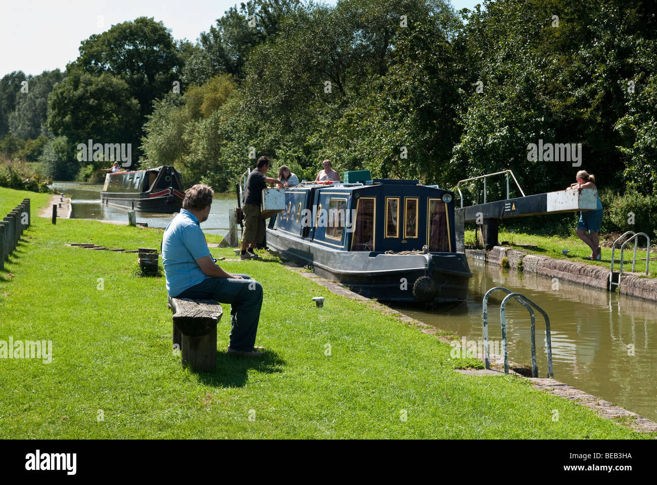 Man sat on rustic bench watching narrow boar enter Lock 68 on Kennet ...