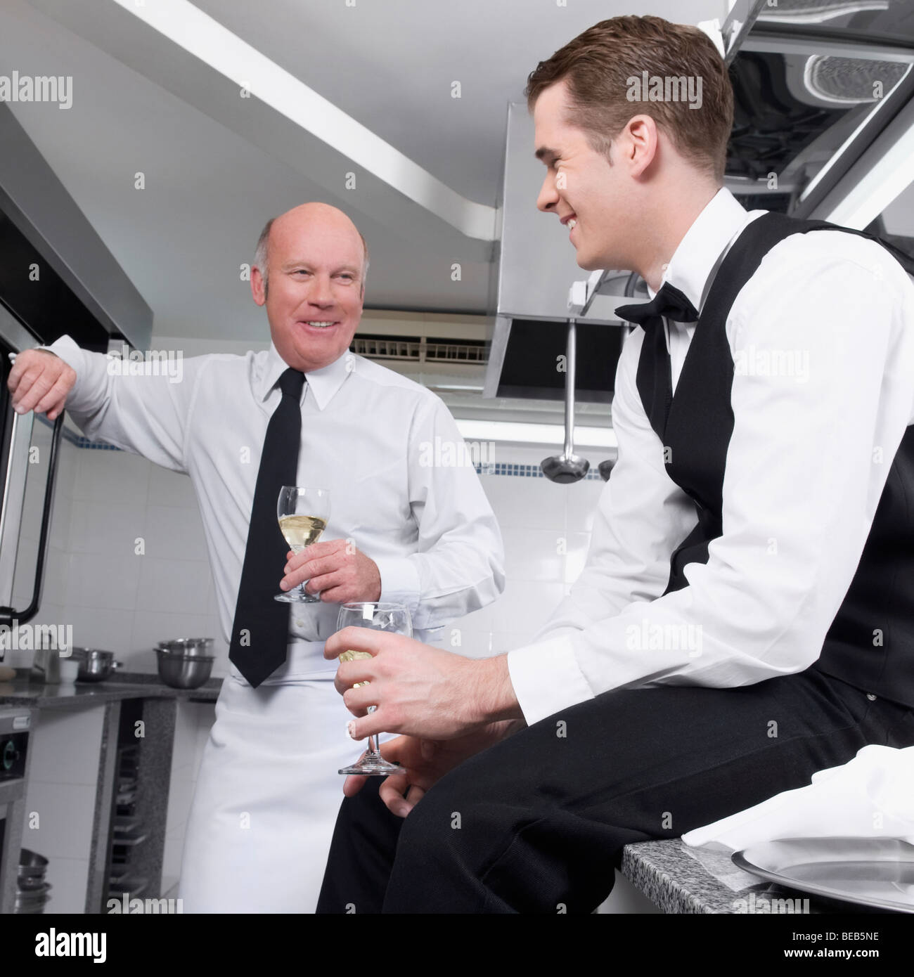 Two waiters drinking wine in the kitchen Stock Photo - Alamy