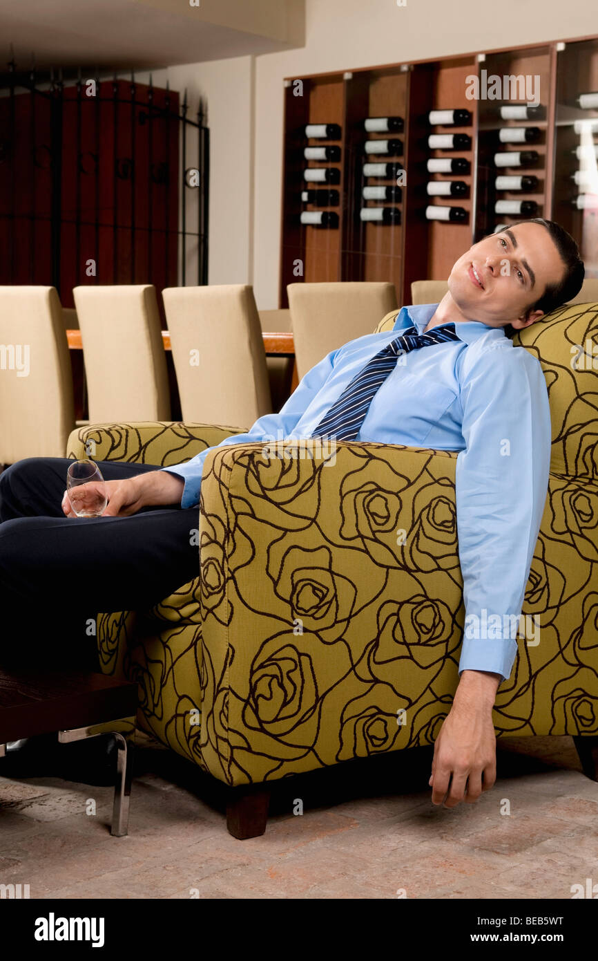 Drunk businessman sitting in an armchair Stock Photo - Alamy