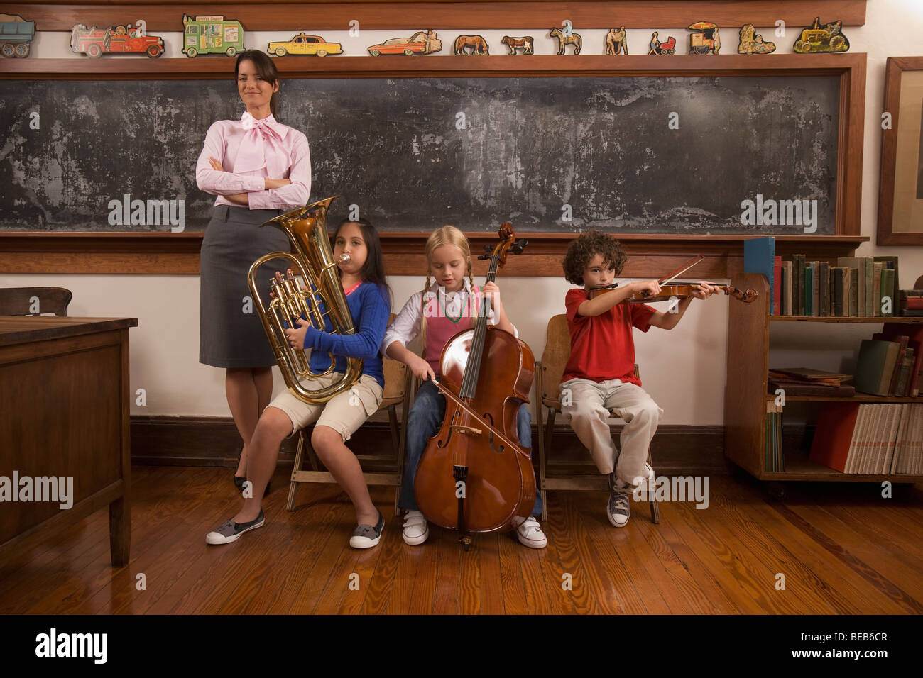 Students playing musical instruments with their teacher standing beside ...