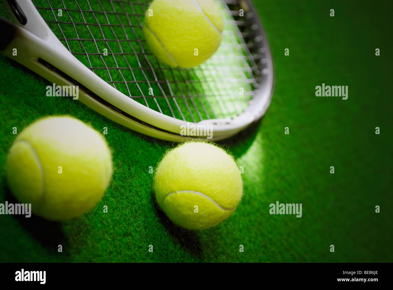 Close-up of three tennis balls with a tennis racket in a court Stock ...