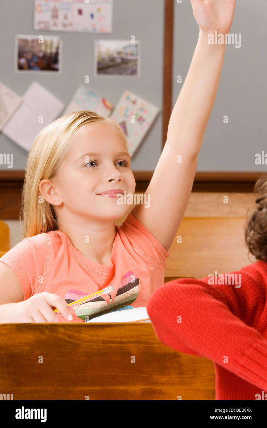 Schoolgirl raising her hand in a classroom Stock Photo - Alamy