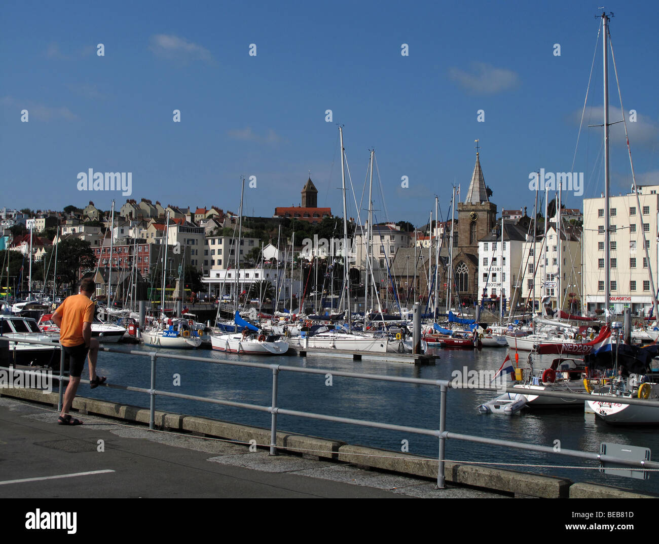 A man looks over the harbour or harbor in St Peter's Port in Guernsey ...