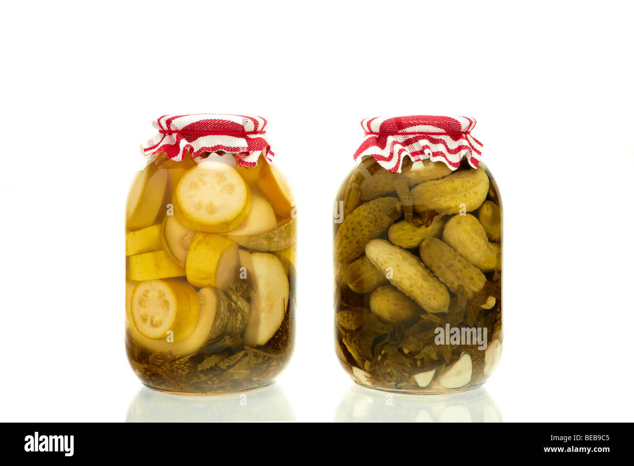 Jars of homemade pickles (vegetable marrow and gherkins) against white ...