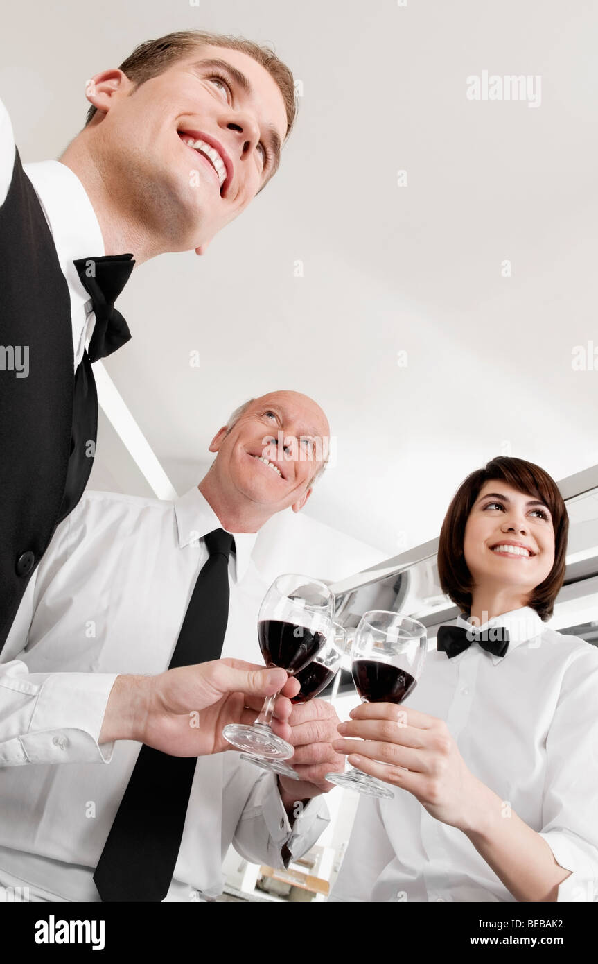Two waiters and a waitress toasting with wine glasses Stock Photo - Alamy