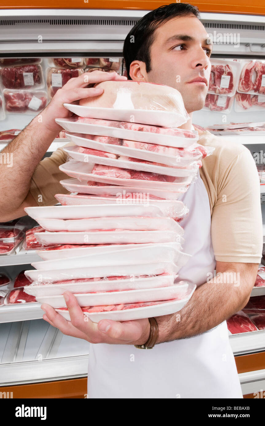 Sales clerk holding a stack of meat in a supermarket Stock Photo - Alamy
