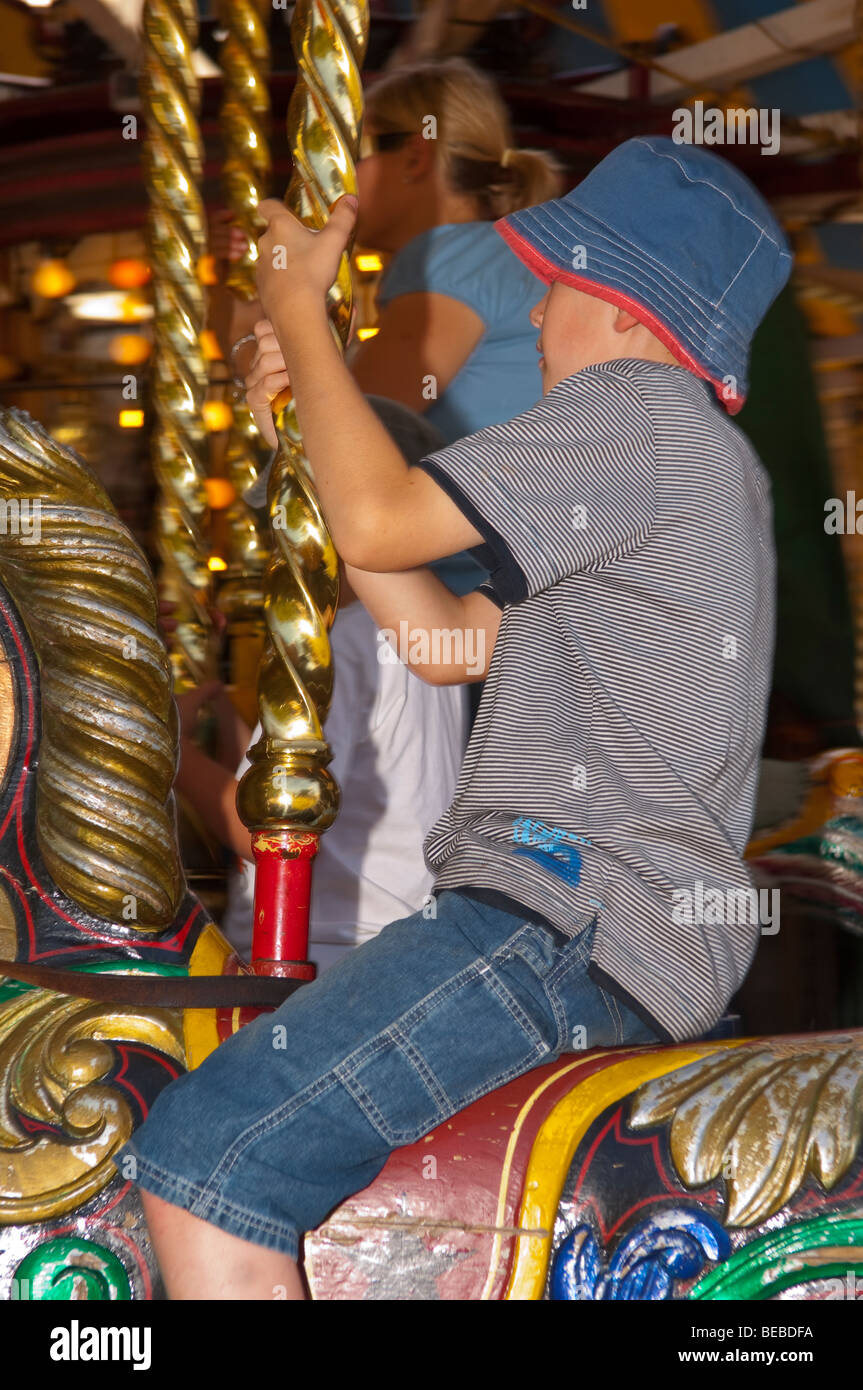 A young boy rides on The Victorian Gallopers Roundabout carousel at ...