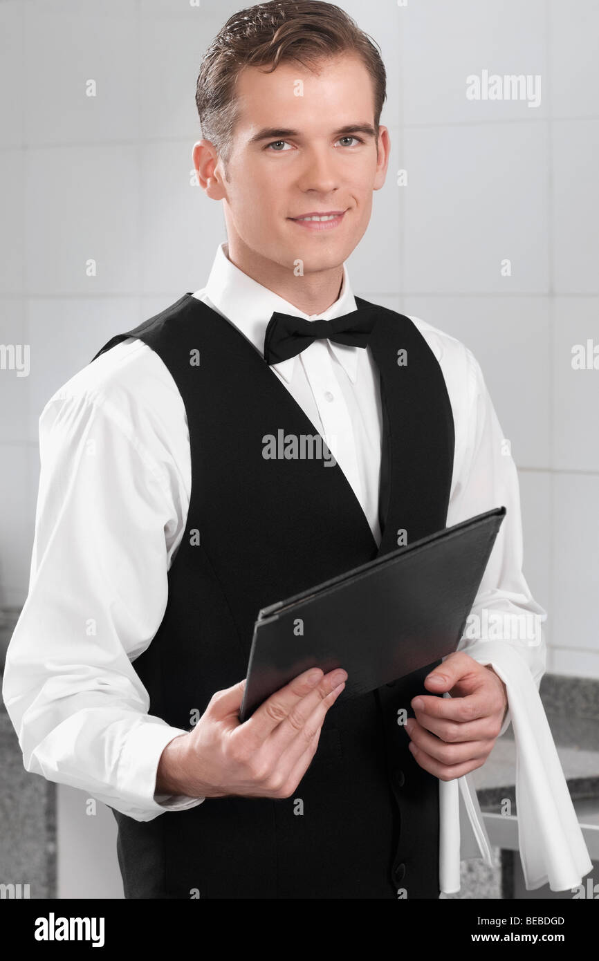 Portrait of a waiter holding a menu in a restaurant Stock Photo - Alamy