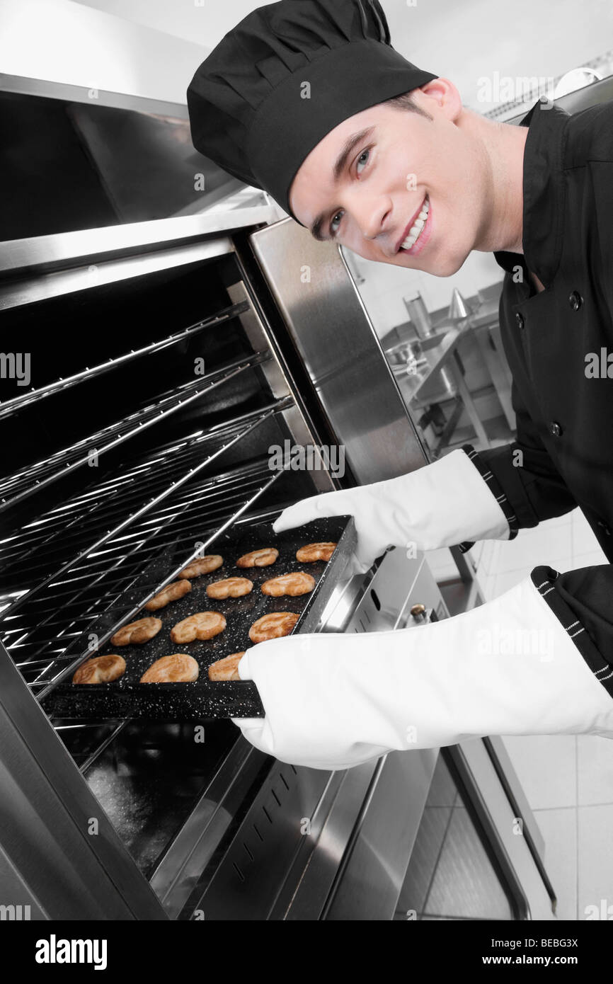 Chef taking out a tray of cookies from an oven Stock Photo - Alamy