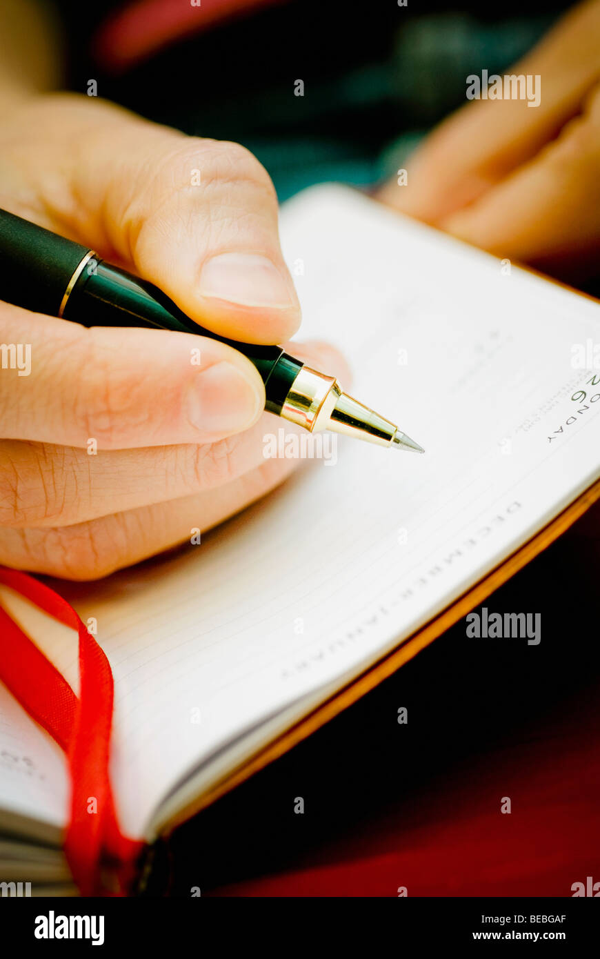 Close-up of a person's hand writing on a diary Stock Photo - Alamy