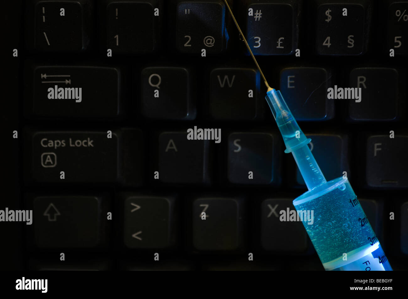 Highlighted syringe over dark keyboard Stock Photo - Alamy