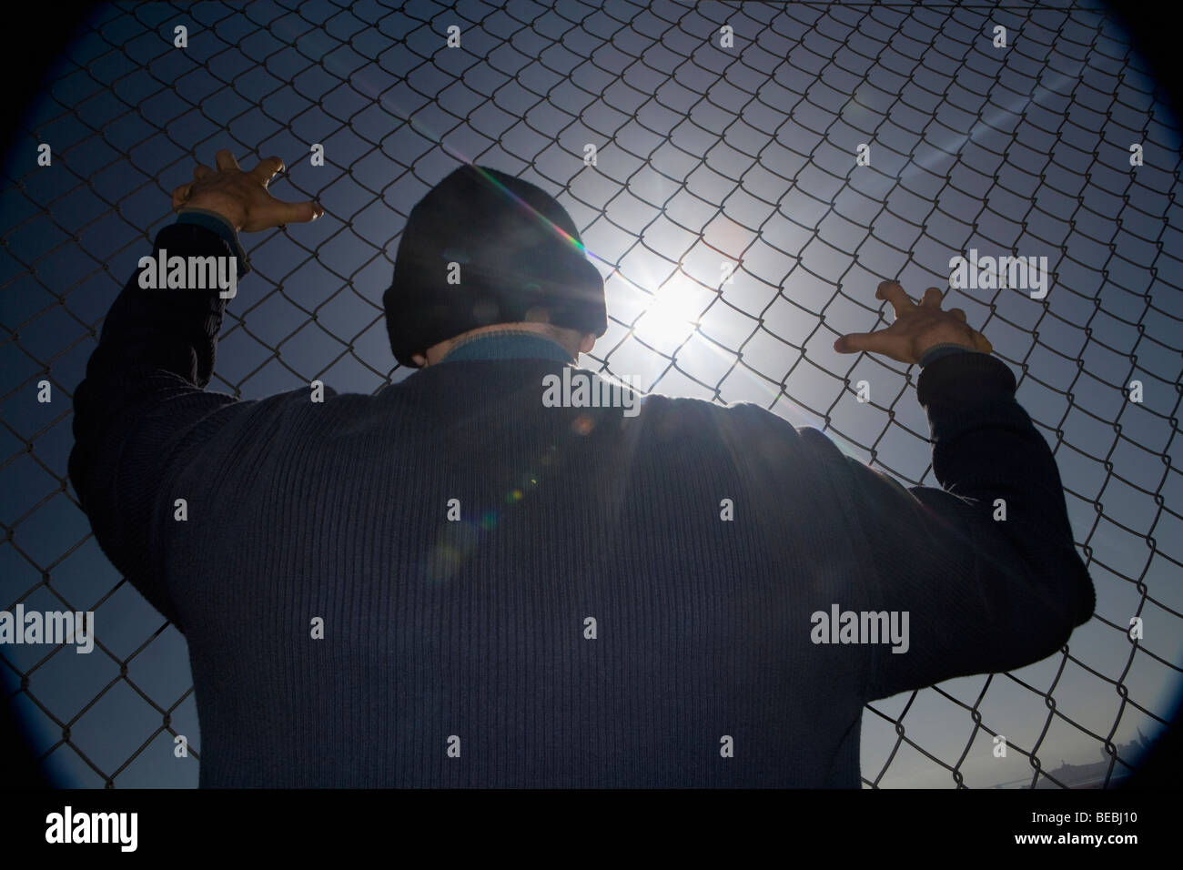 Prisoner clinging to a chainlink fence Stock Photo - Alamy