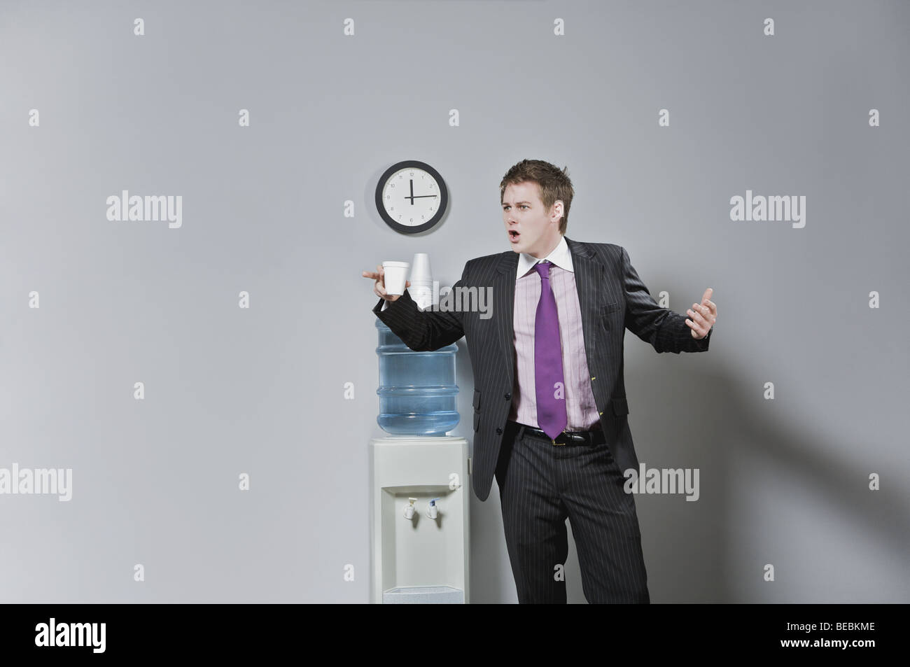 Businessman looking surprised near a water cooler Stock Photo - Alamy