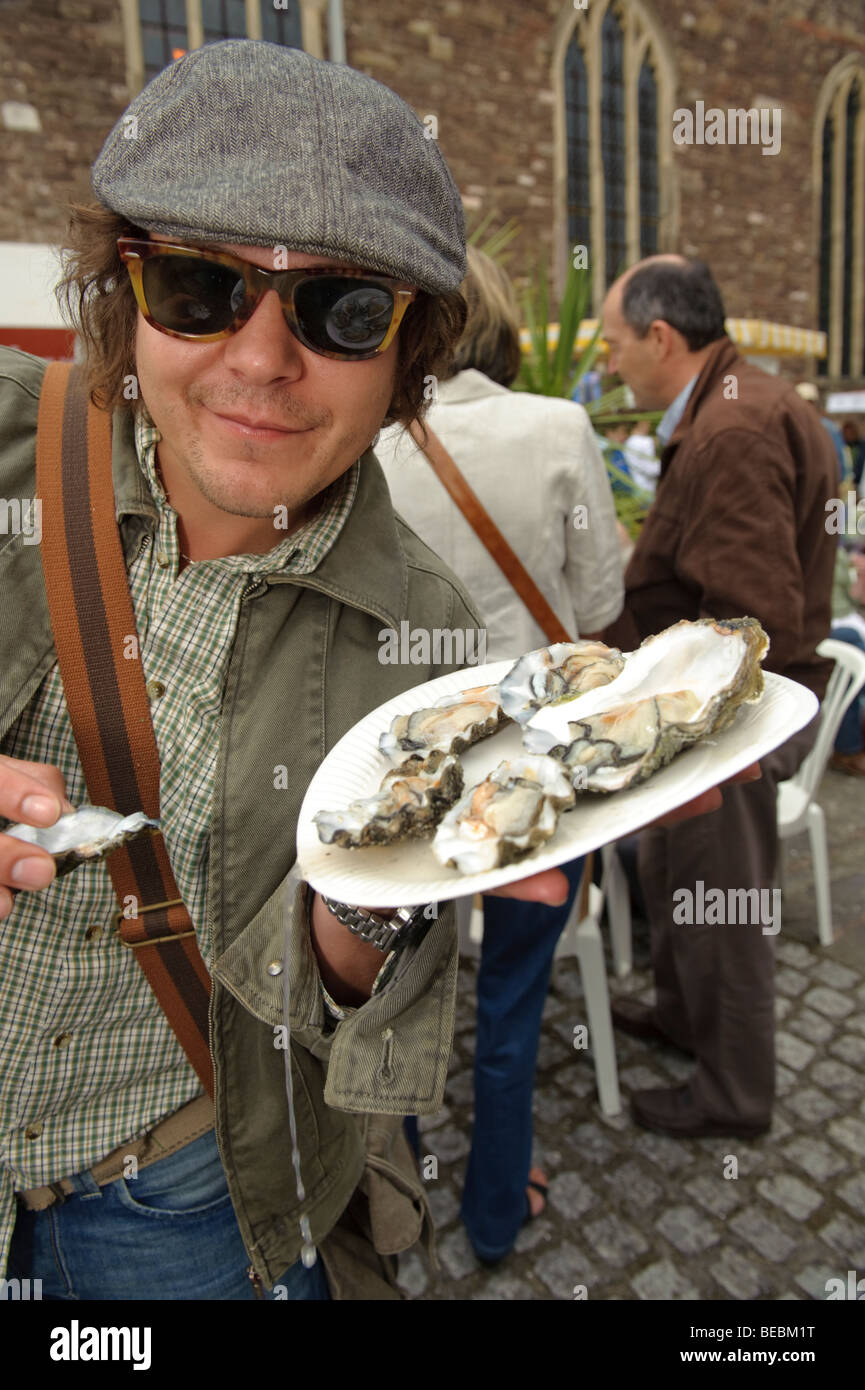 A young man eating fresh oysters at the Abergavenny food festival ...