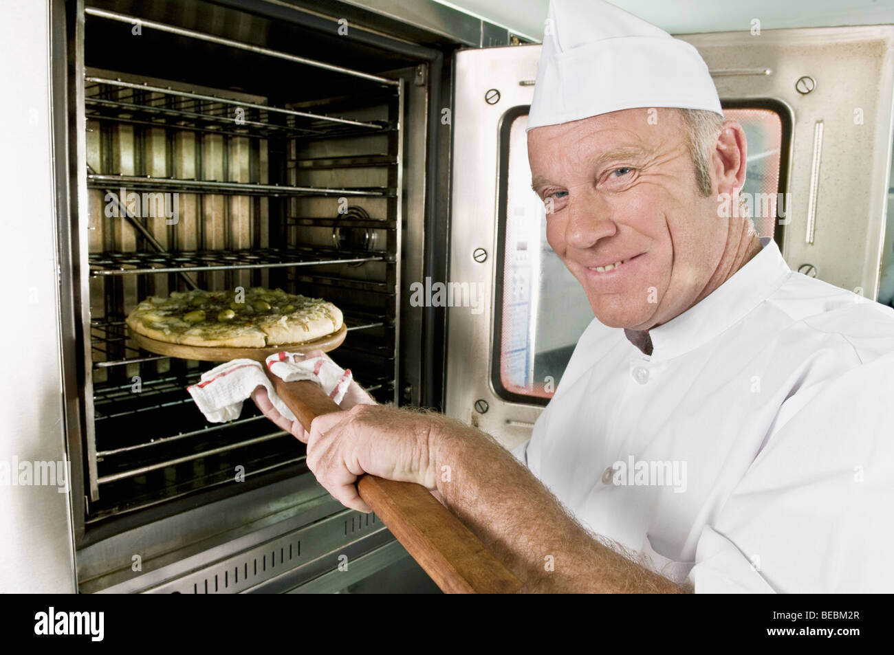 Chef putting a pizza into an oven Stock Photo - Alamy