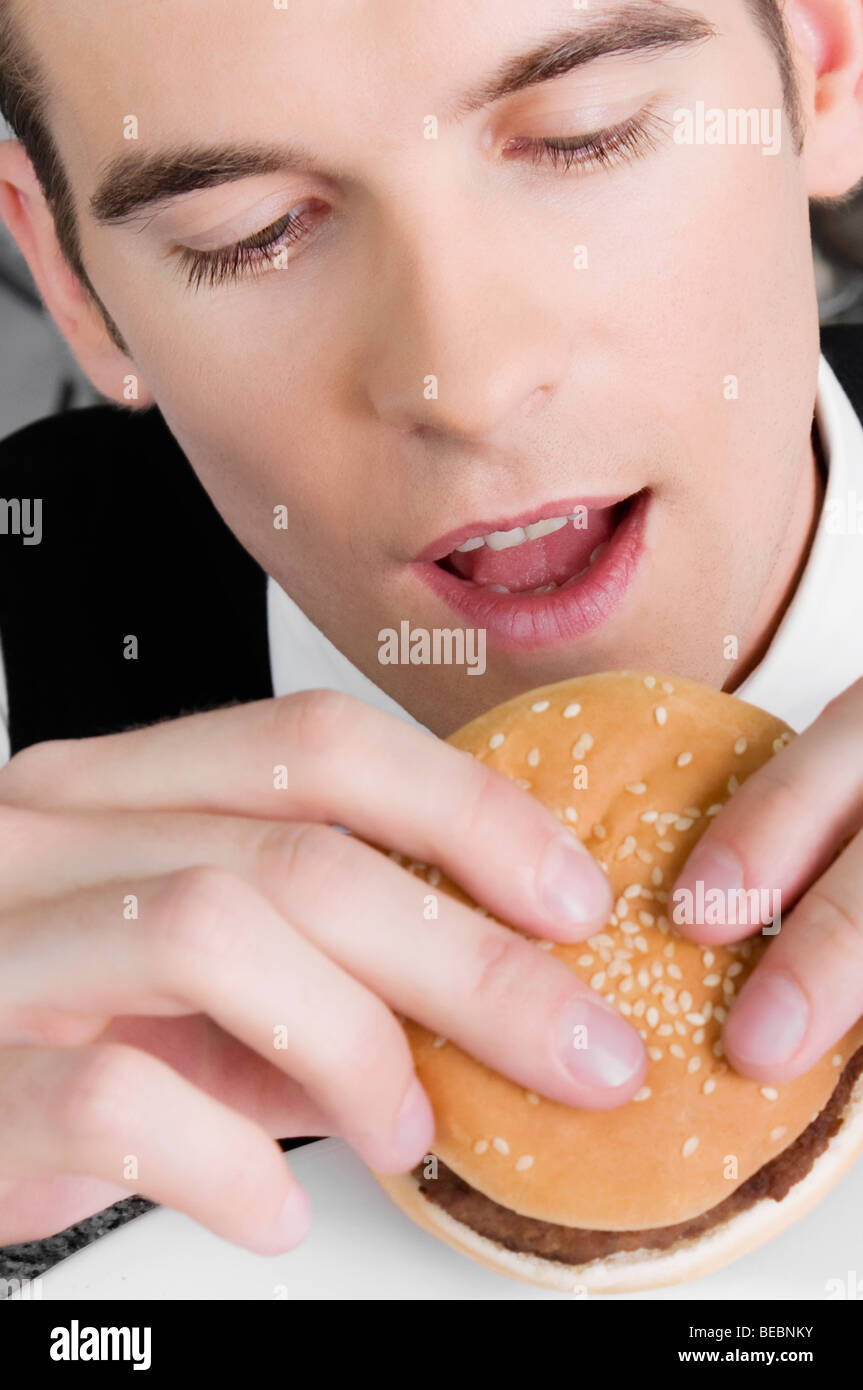 Close-up of a waiter eating a burger Stock Photo - Alamy