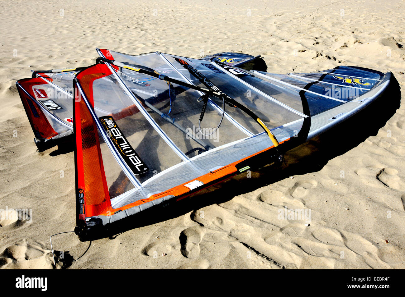 Colourful Windsurfing Boards And Sails Laying On A Sandy Beach Waiting ...