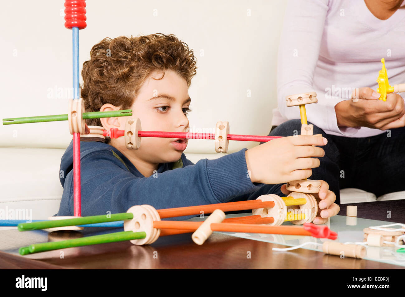 Woman assisting her son in assembling a toy Stock Photo - Alamy