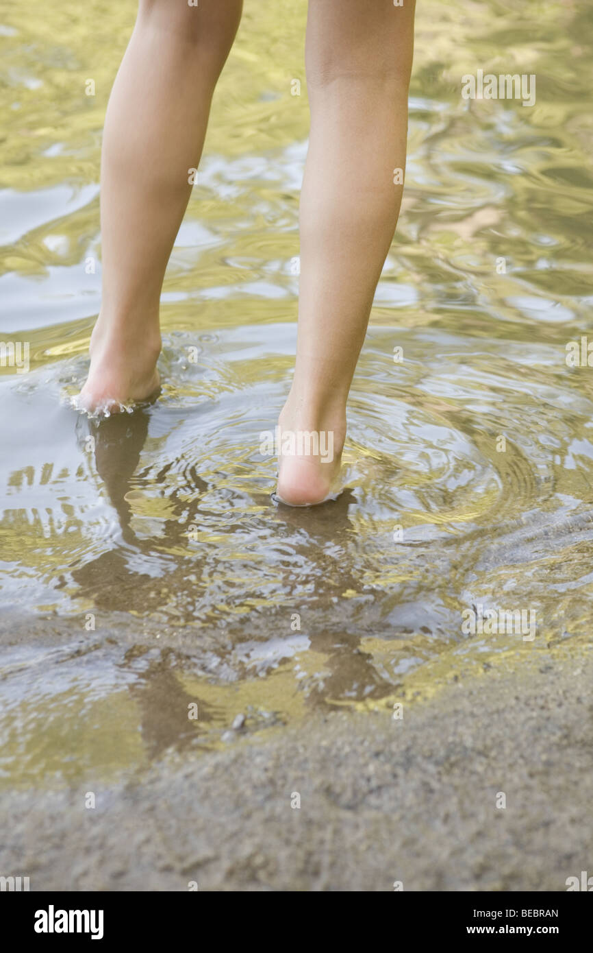 Low section view of a person walking through a puddle Stock Photo - Alamy
