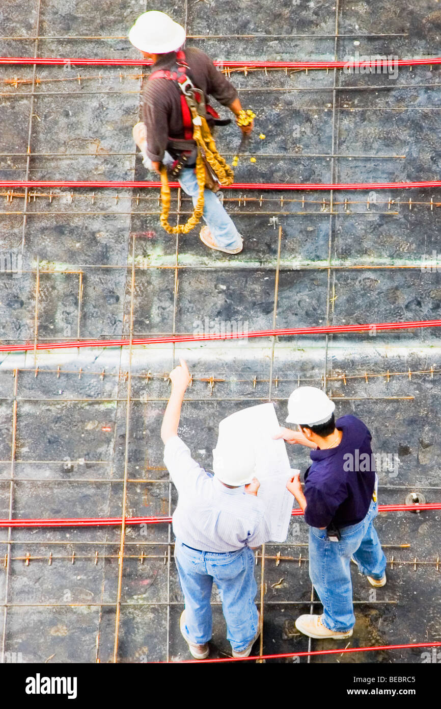 High angle view of two architects standing with a construction worker ...