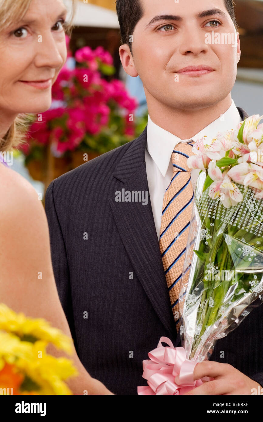 Female florist giving a bouquet of flowers to a customer Stock Photo ...