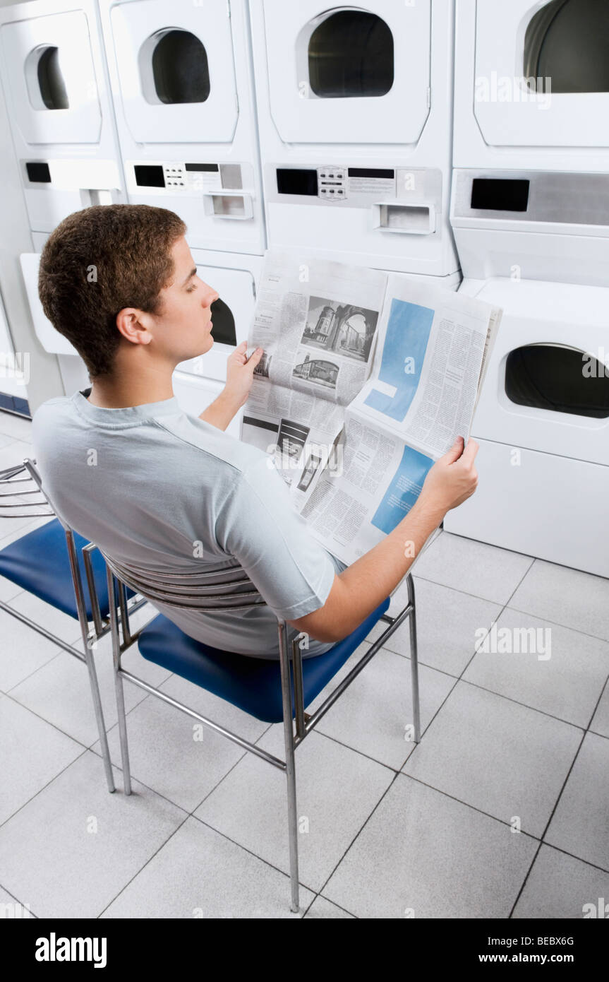 Man reading a newspaper in a laundromat Stock Photo - Alamy
