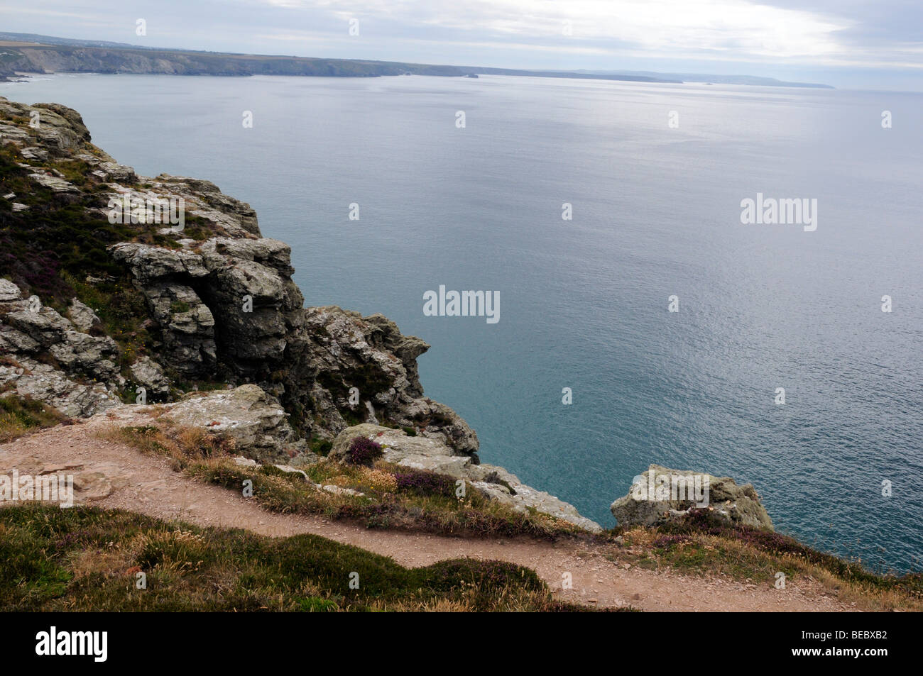 British Coastline of Cornwall with a glass like sea and blue cloudy sky ...