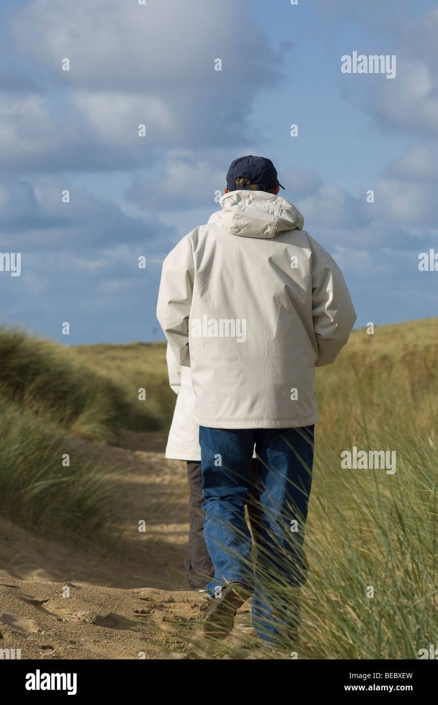 Man & woman walking through the sand dunes Stock Photo - Alamy