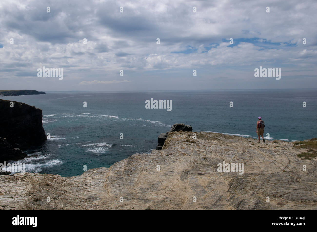 Female walker on the cliff edge of the Cornish coastal path under a ...