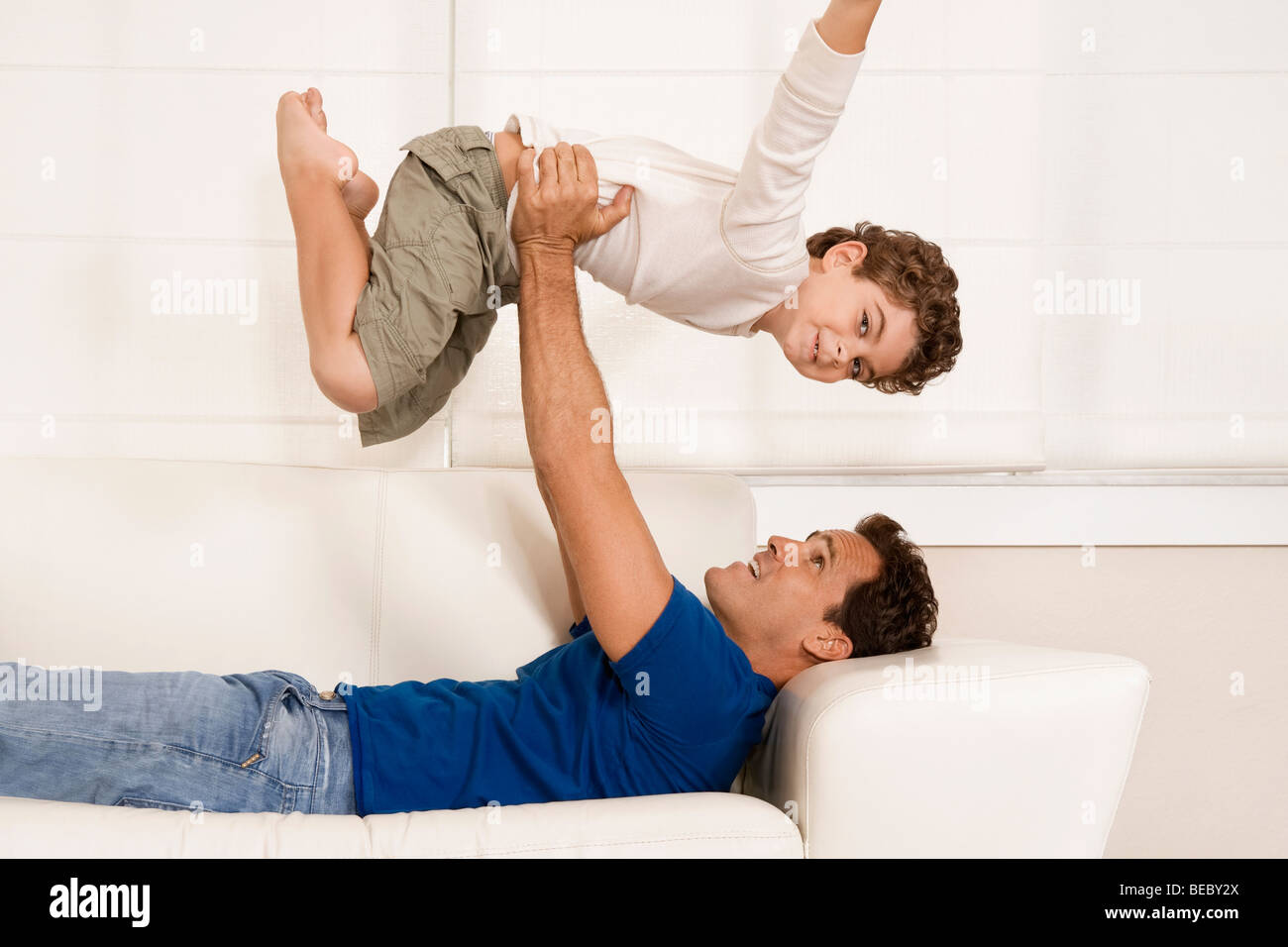 Man playing with his son on a couch Stock Photo - Alamy