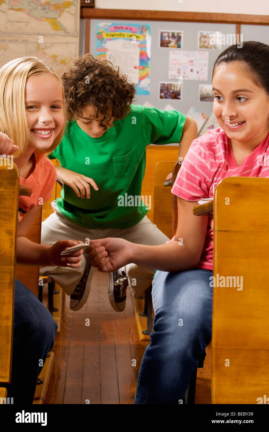 Two schoolgirls passing note during exam in a classroom Stock Photo - Alamy