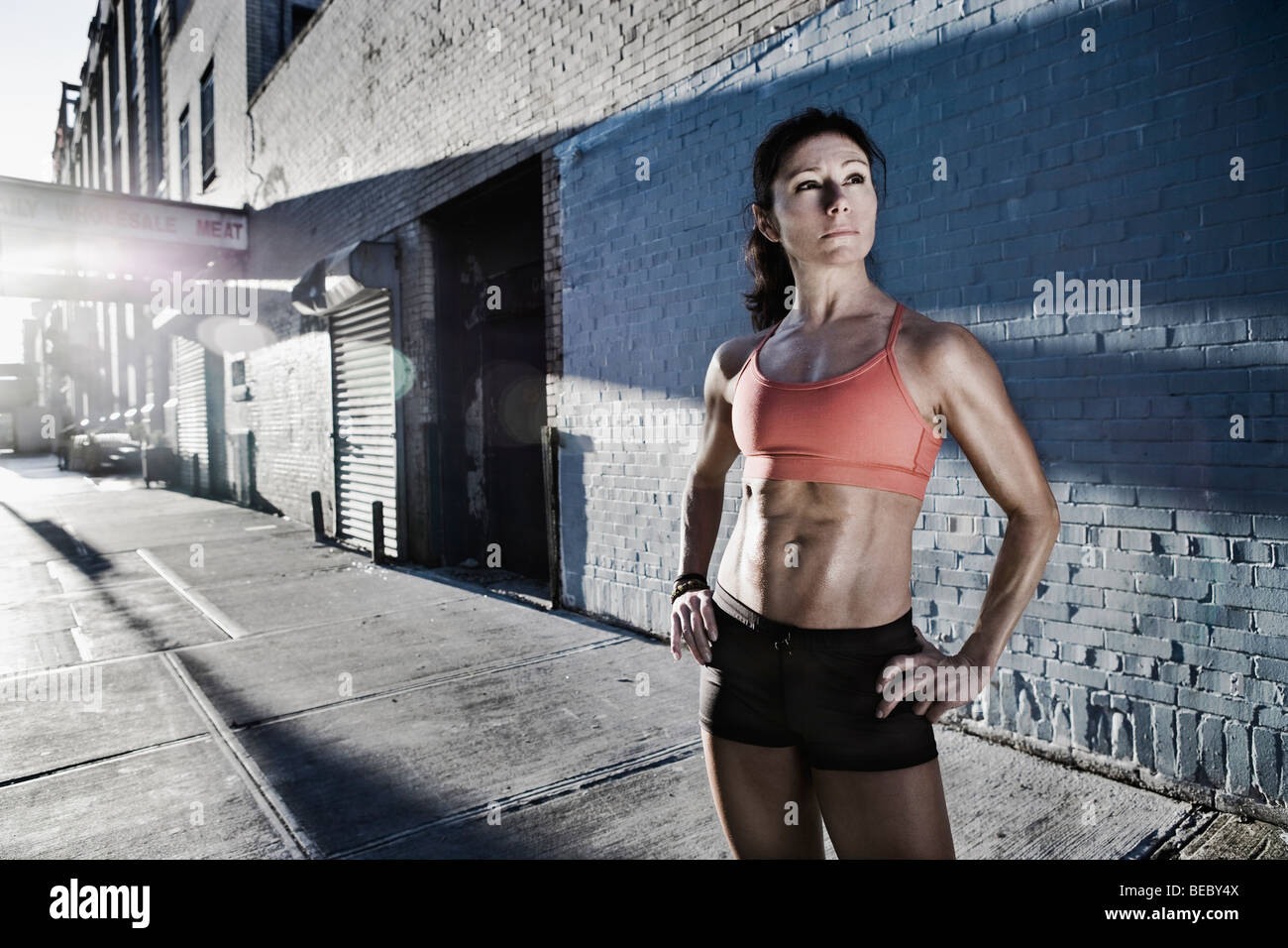 Woman standing with arms akimbo and thinking Stock Photo - Alamy