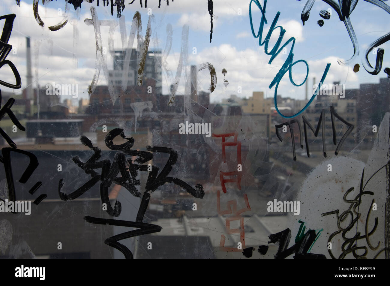 A window covered in graffiti looks out on the buildings of the trendy ...