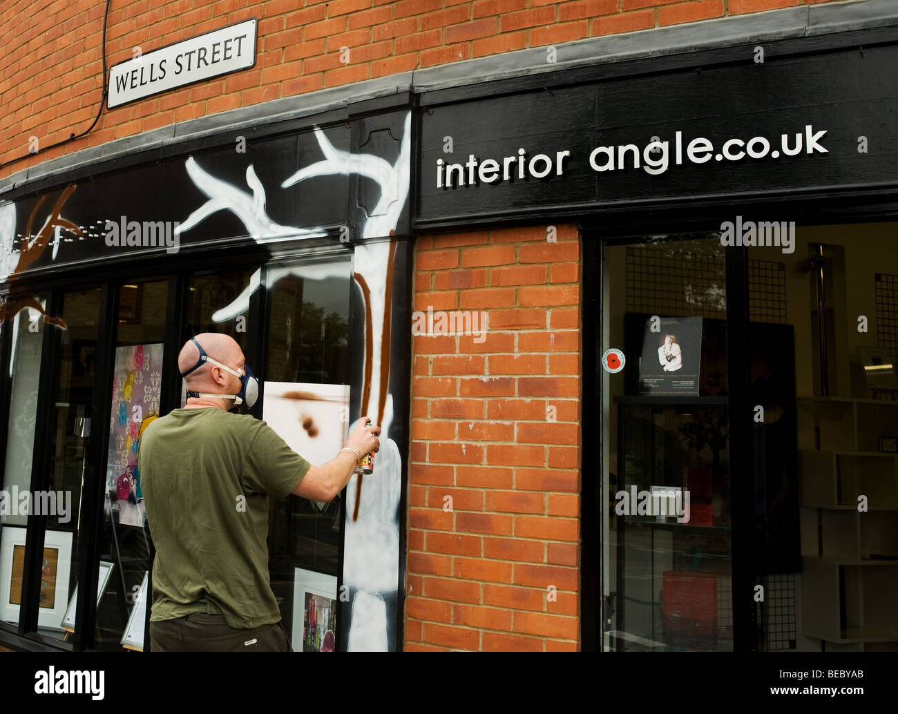 Tom Lewis street artist creating a mural on the window of an art ...
