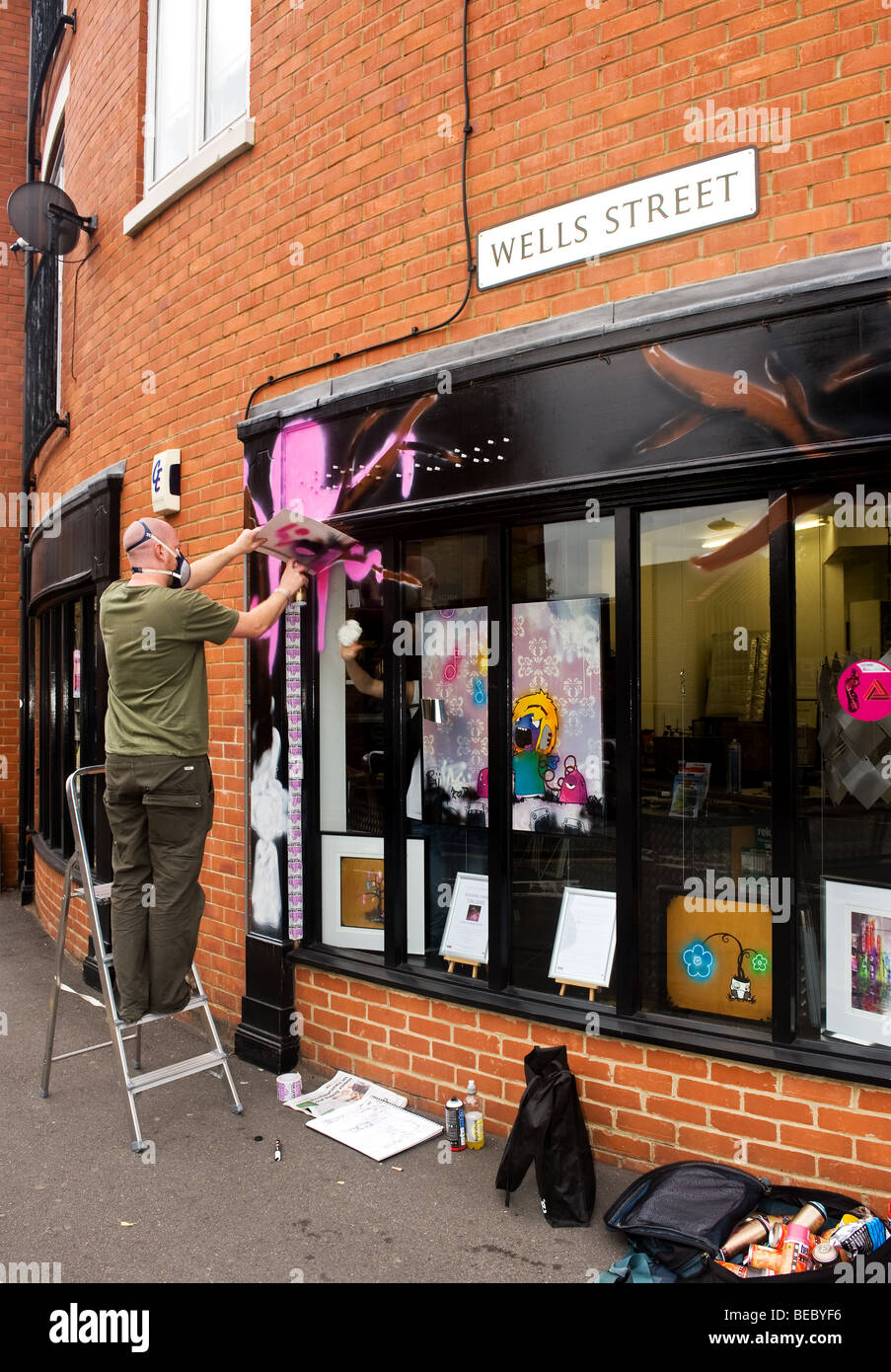Tom Lewis street artist working on a mural on the window of an art ...