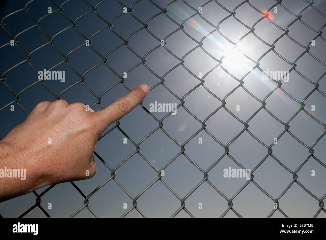 Person pointing towards the sun through chainlink fence Stock Photo - Alamy