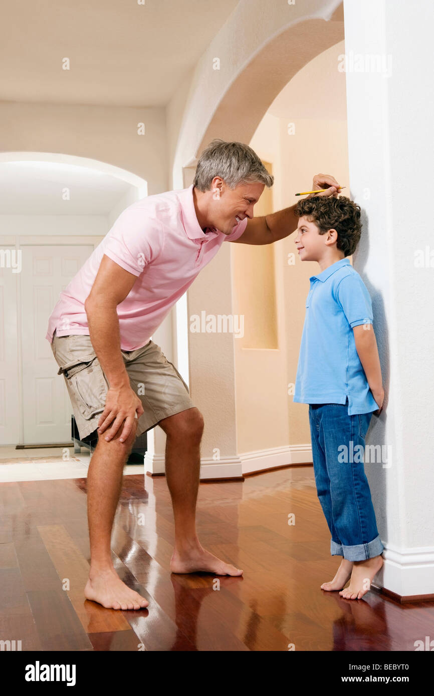 Man measuring his son's height Stock Photo - Alamy