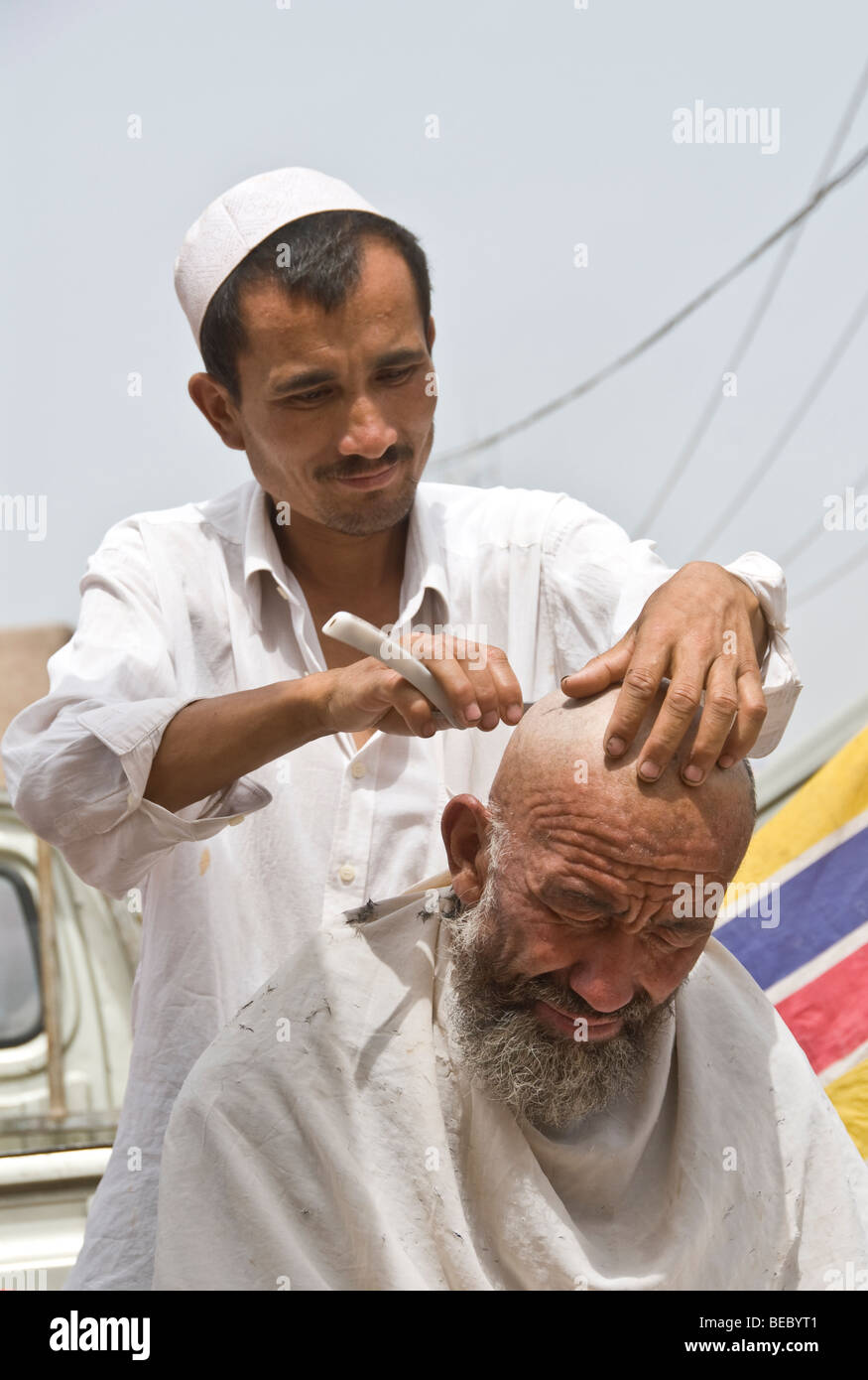 Barber working in a street market of Kashgar, Xinjiang Province, China ...