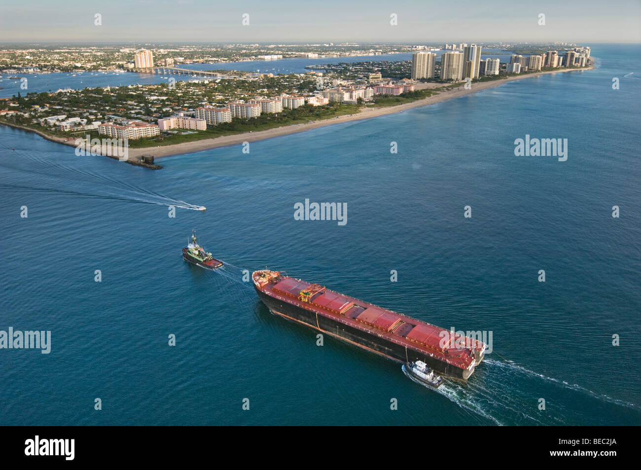large red barge being guided by tug boats in ocean Stock Photo - Alamy